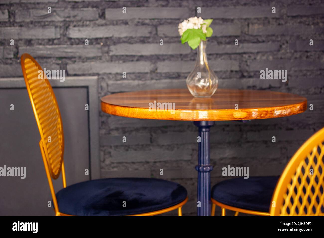 Round wooden table in cafe, restaurant terrace against black stone ...