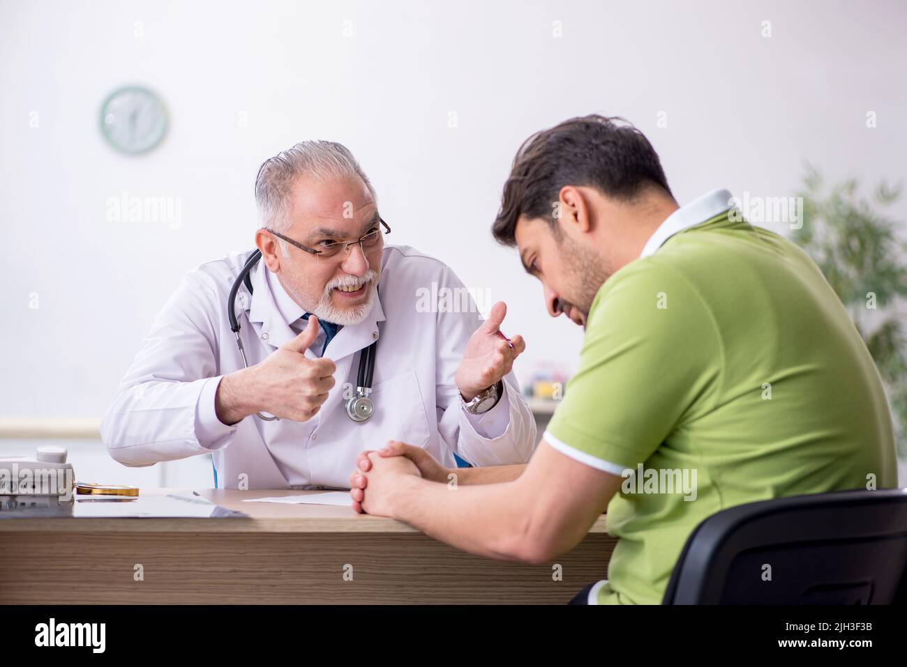 Young man visiting old doctor Stock Photo - Alamy