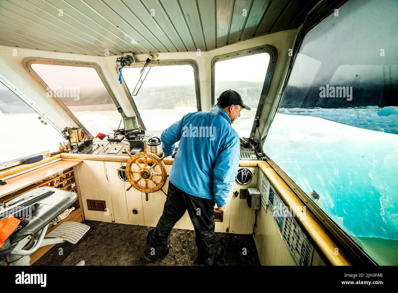 Perspective. Ferry boat captain maneuvers boat near iceberg on Lake ...