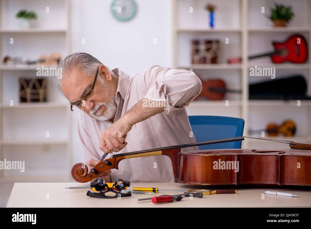 Old repairman repairing musical instruments at workshop Stock Photo - Alamy