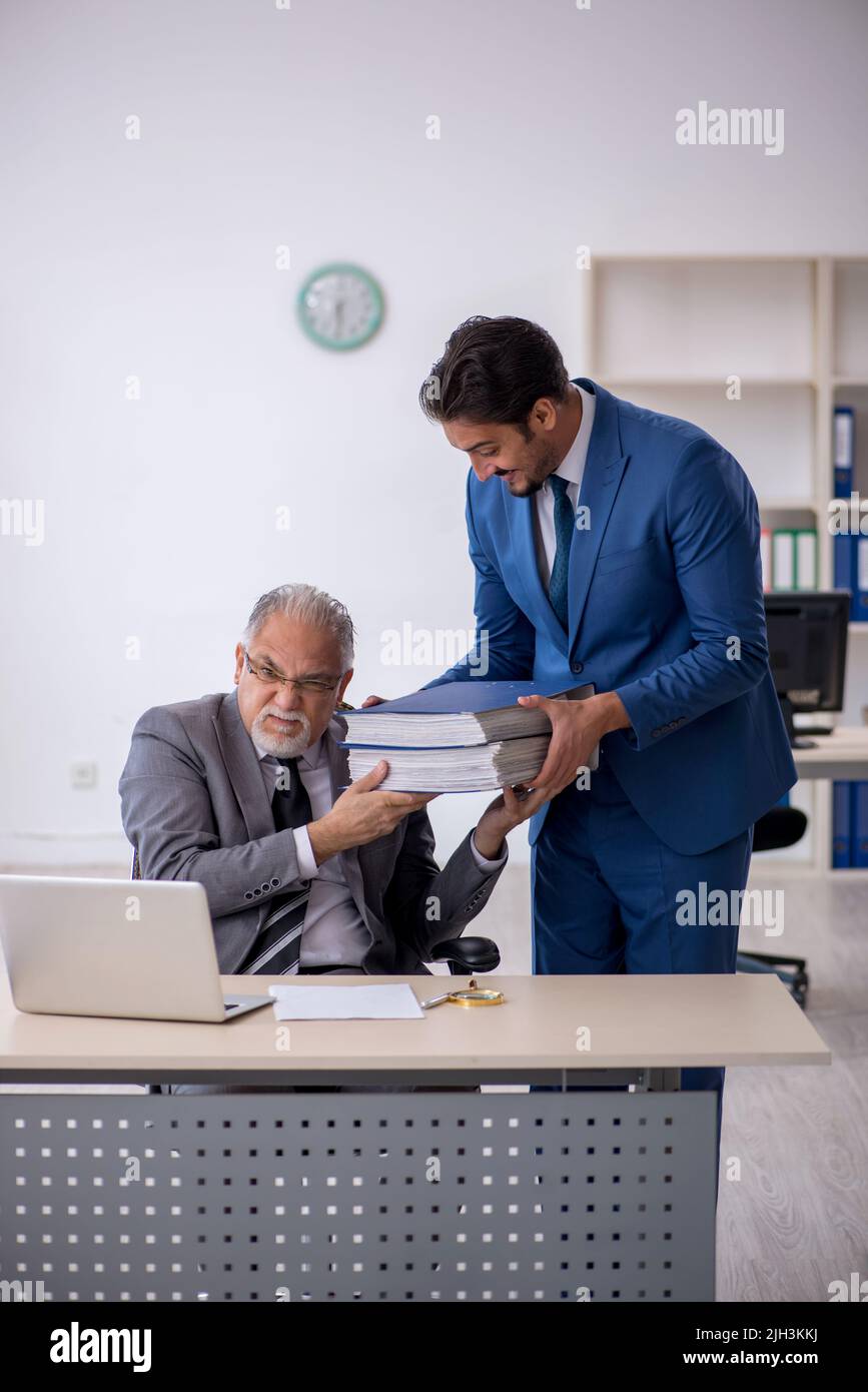 Old boss and young employee working at workplace Stock Photo - Alamy
