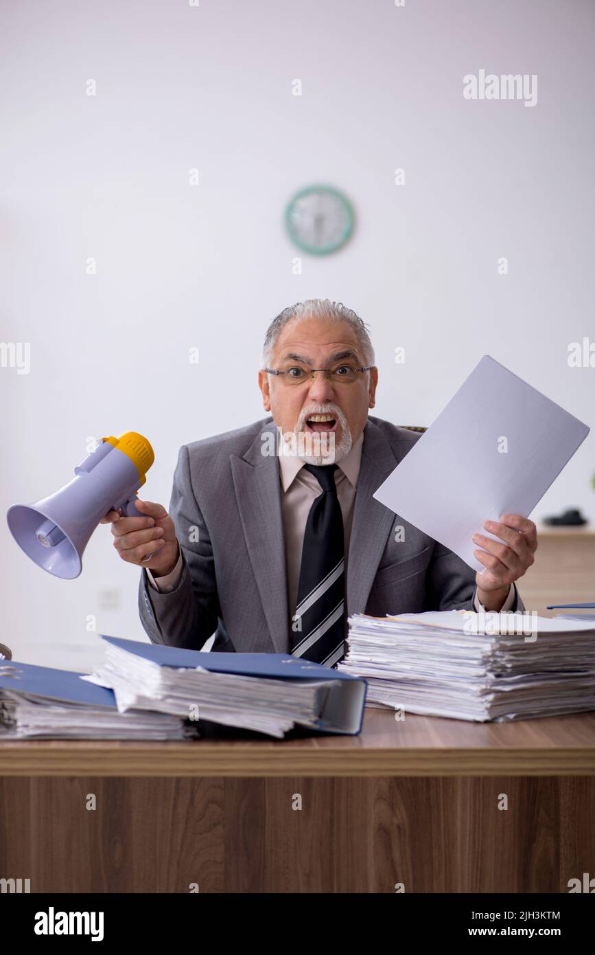 Old male boss holding megaphone at workplace Stock Photo - Alamy