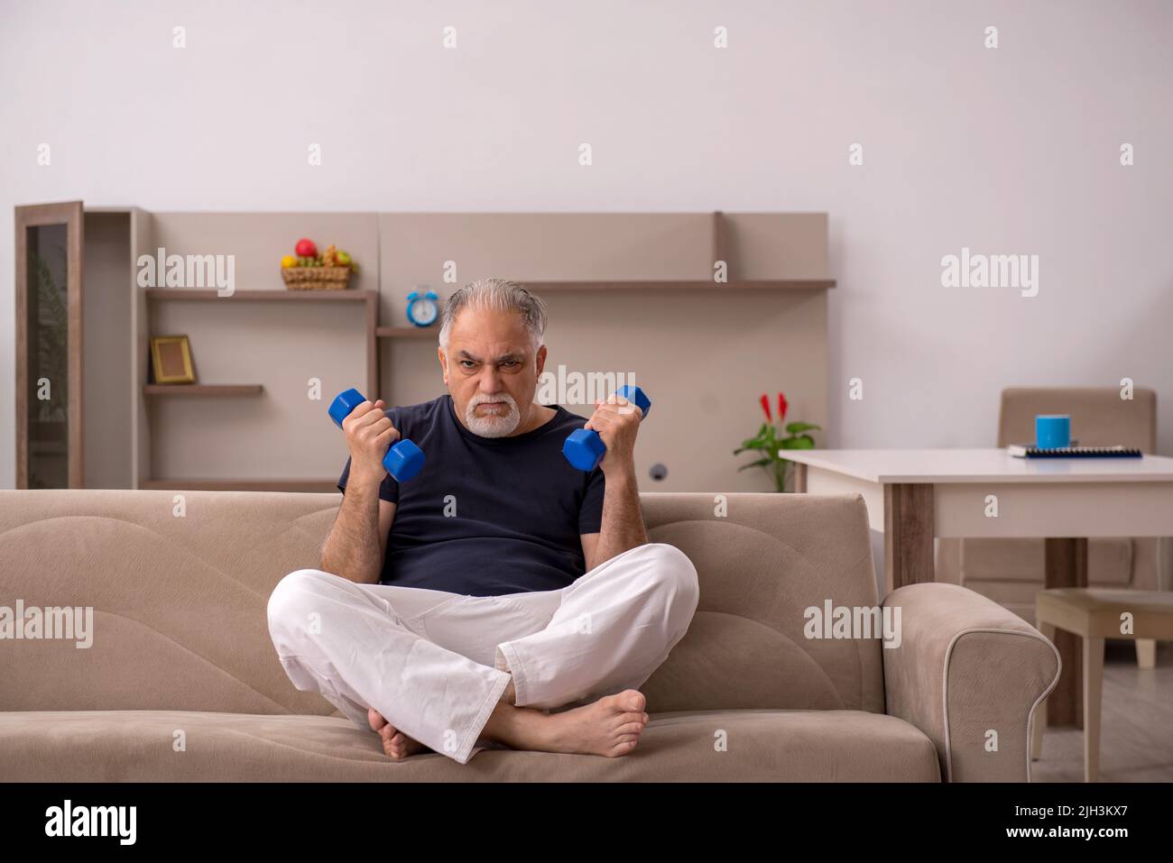 Old man doing sport exercises indoors Stock Photo - Alamy