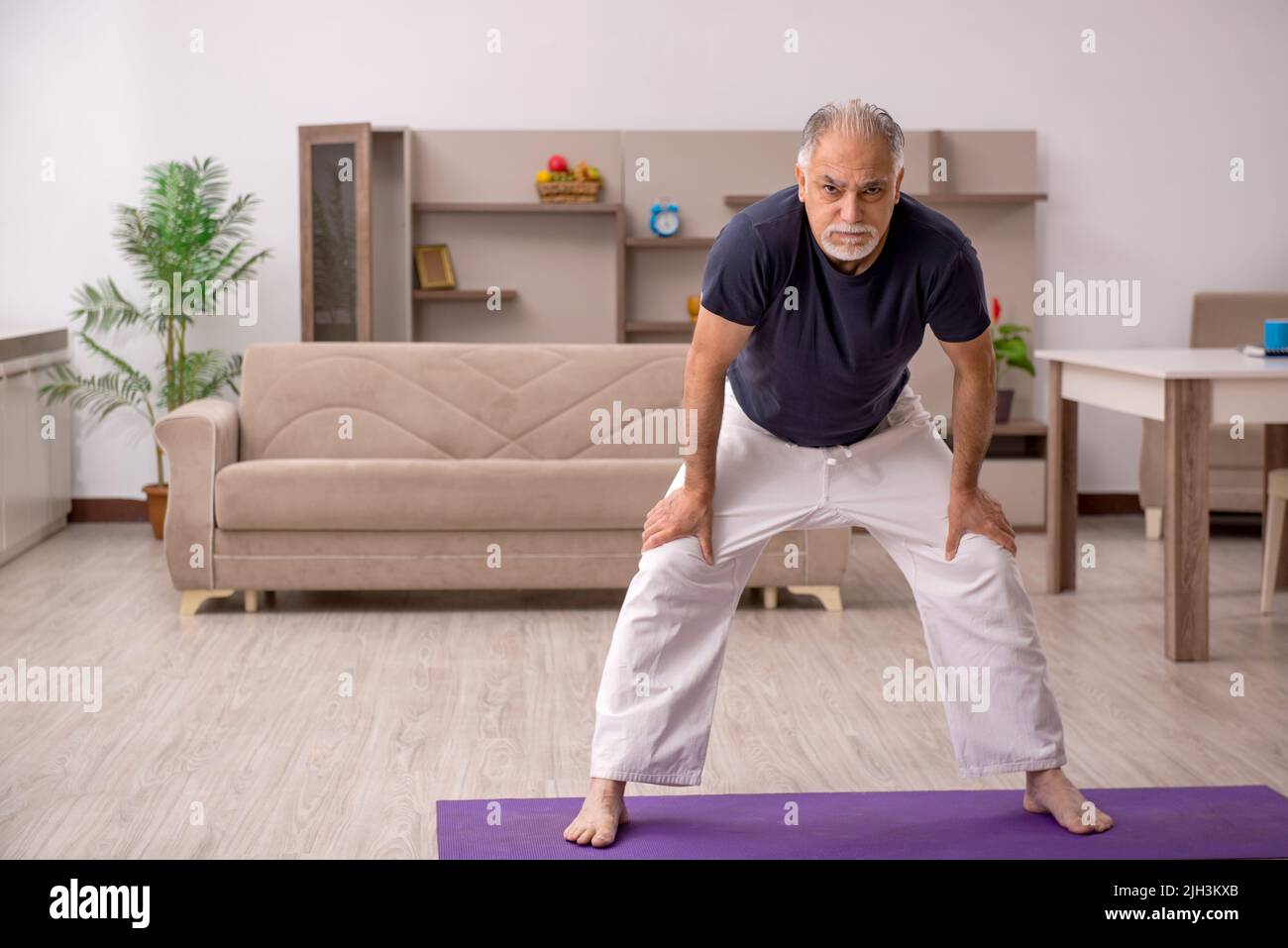 Old man doing sport exercises indoors Stock Photo - Alamy