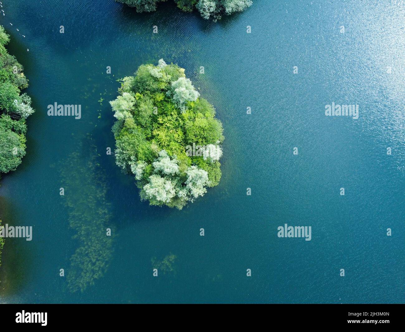 Aerial down view of island on a tranquil clear water lake in ...