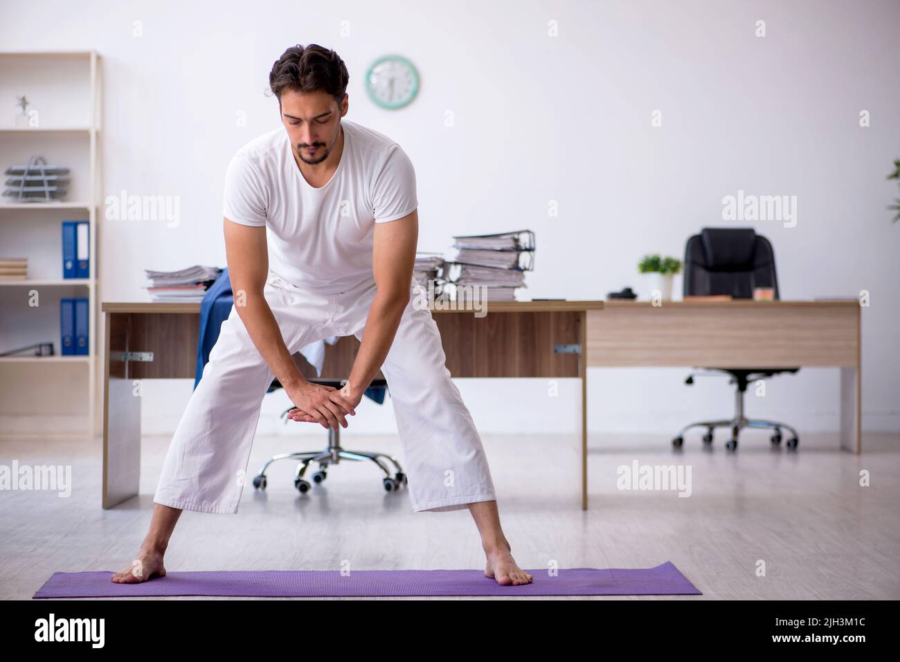 Young businessman employee doing sport exercises at workplace Stock ...