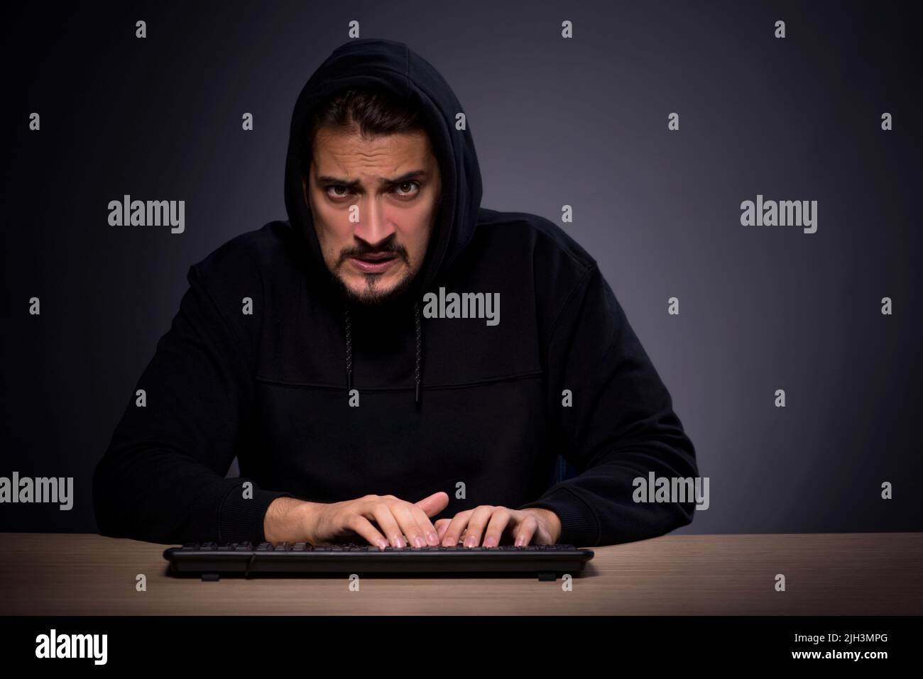 Young hacker on grey background Stock Photo - Alamy