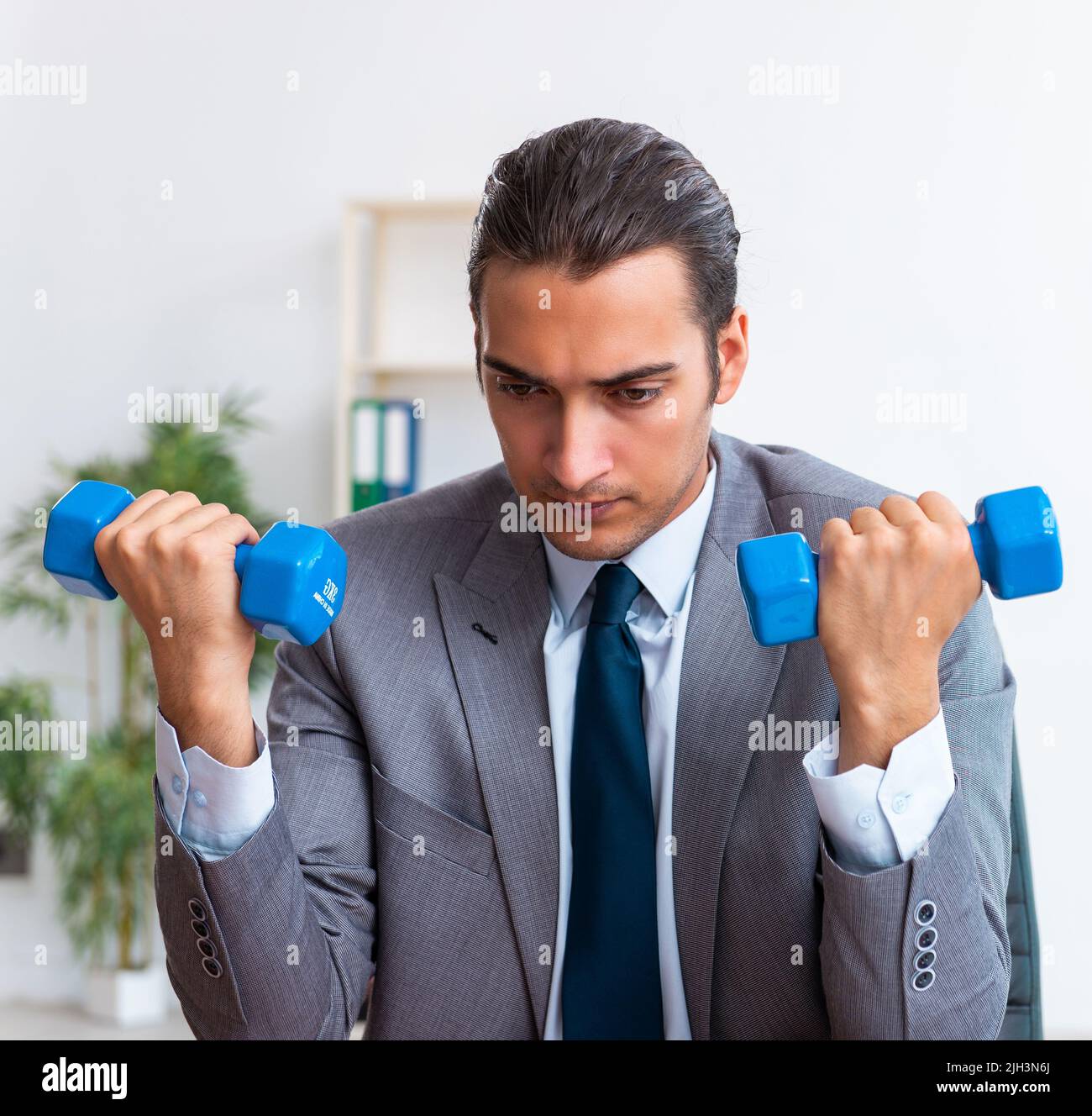 The young handsome employee doing sport exercises at workplace Stock ...