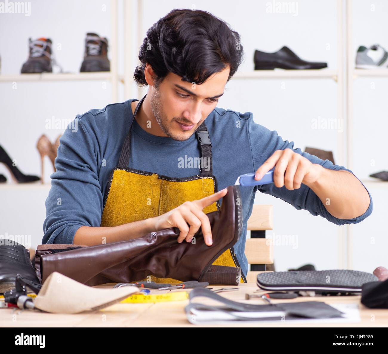 Young man repairing shoes in workshop Stock Photo - Alamy