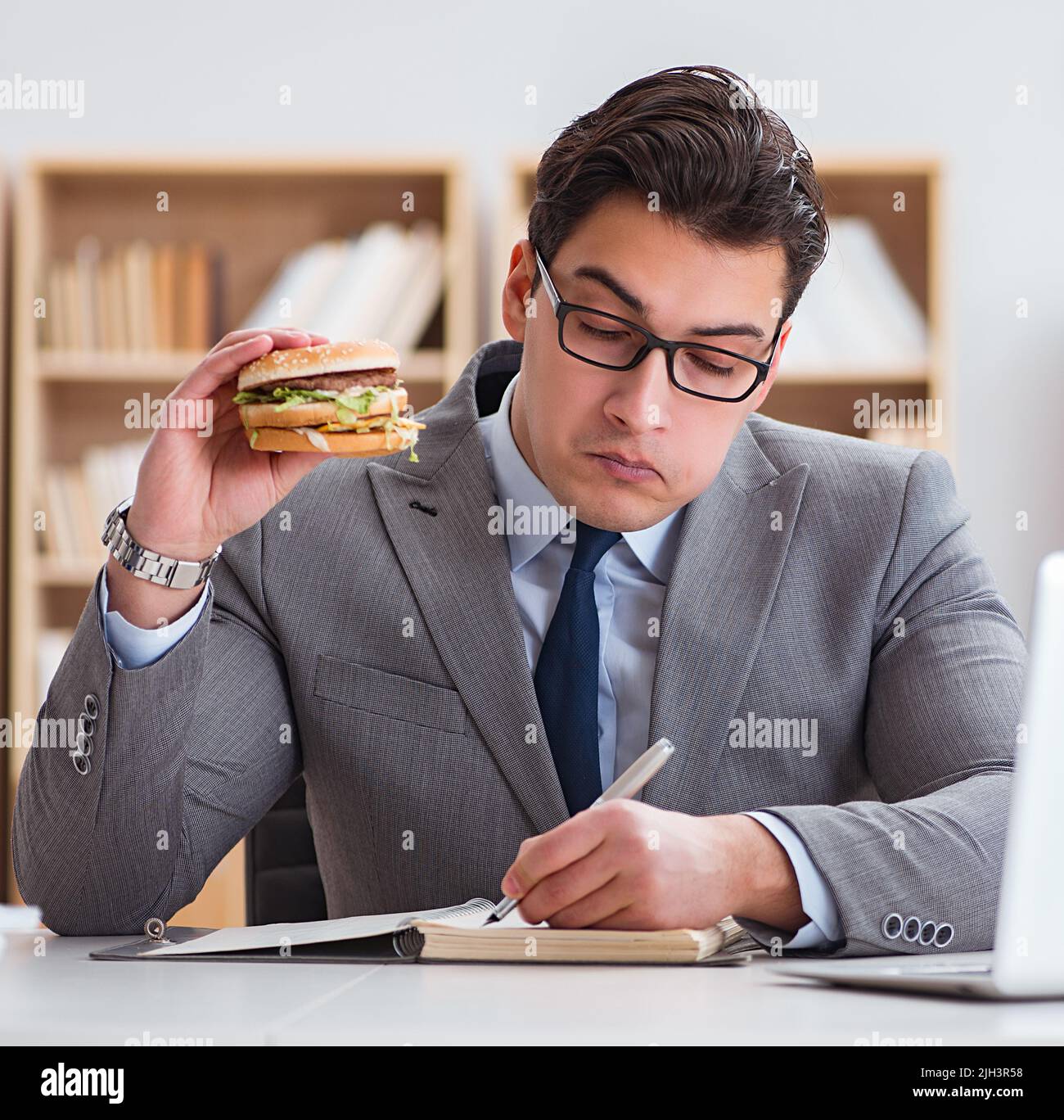 The hungry funny businessman eating junk food sandwich Stock Photo - Alamy