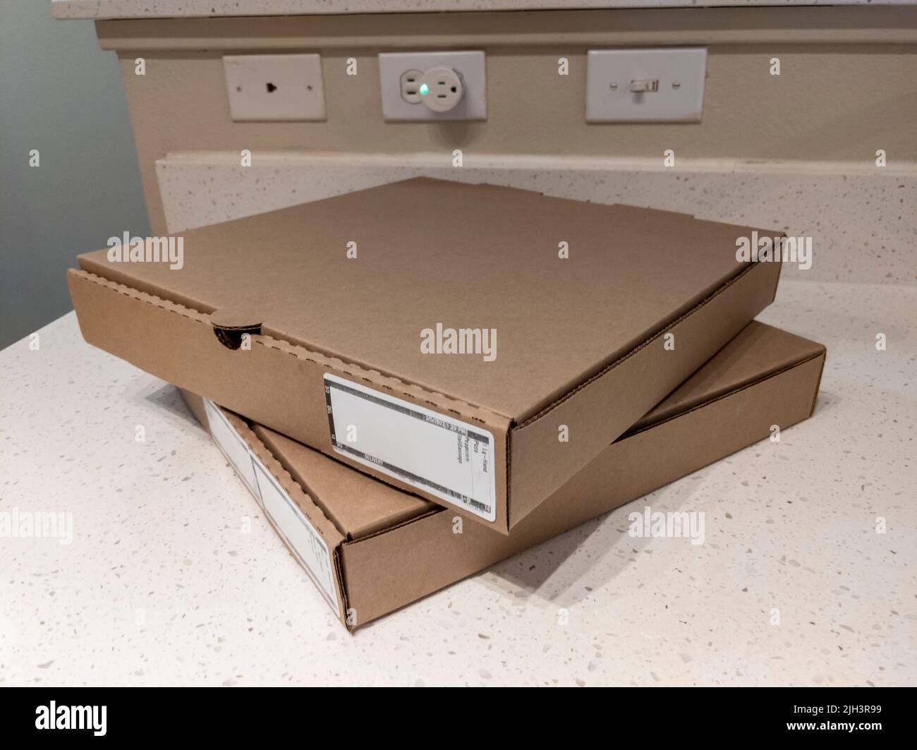 Close up view of two cardboard pizza boxes on a kitchen counter top ...