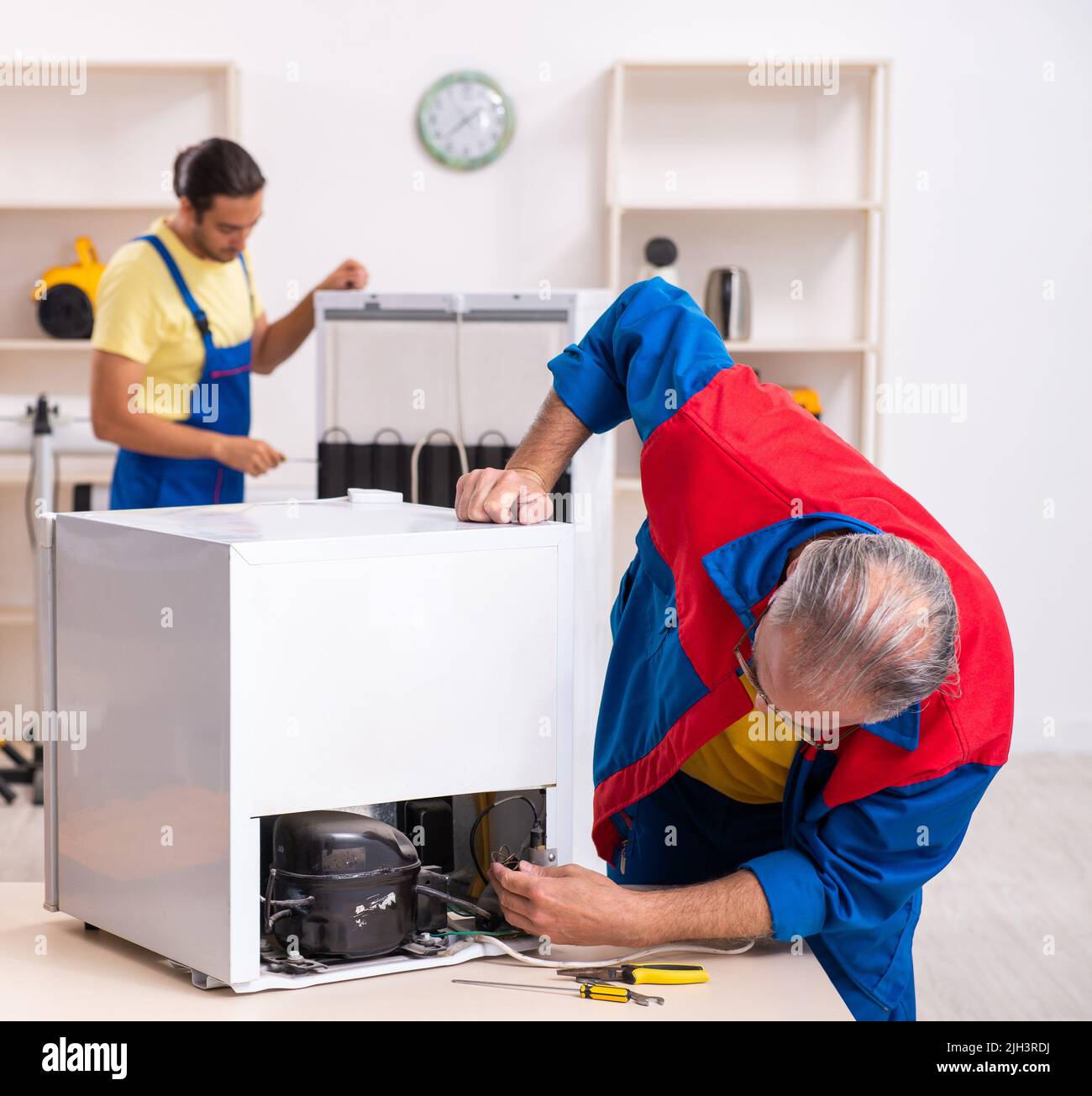 The two contractors repairing fridge at workshop Stock Photo - Alamy