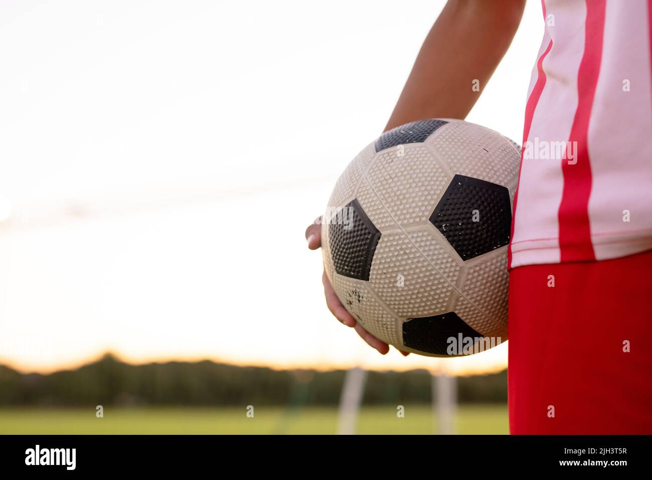 Midsection of caucasian male soccer player in red jersey holding ball ...