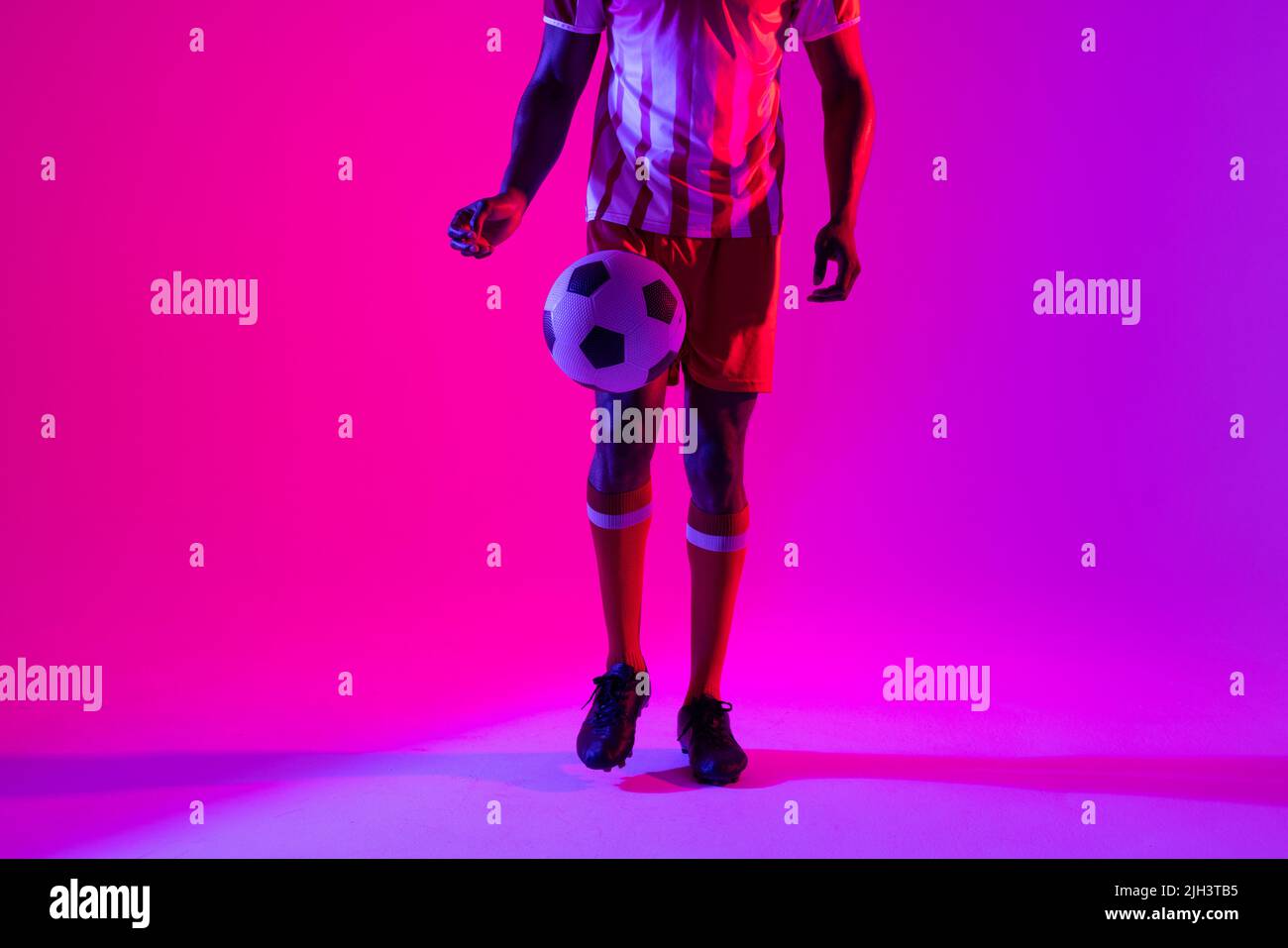African american male soccer player with football over neon pink ...