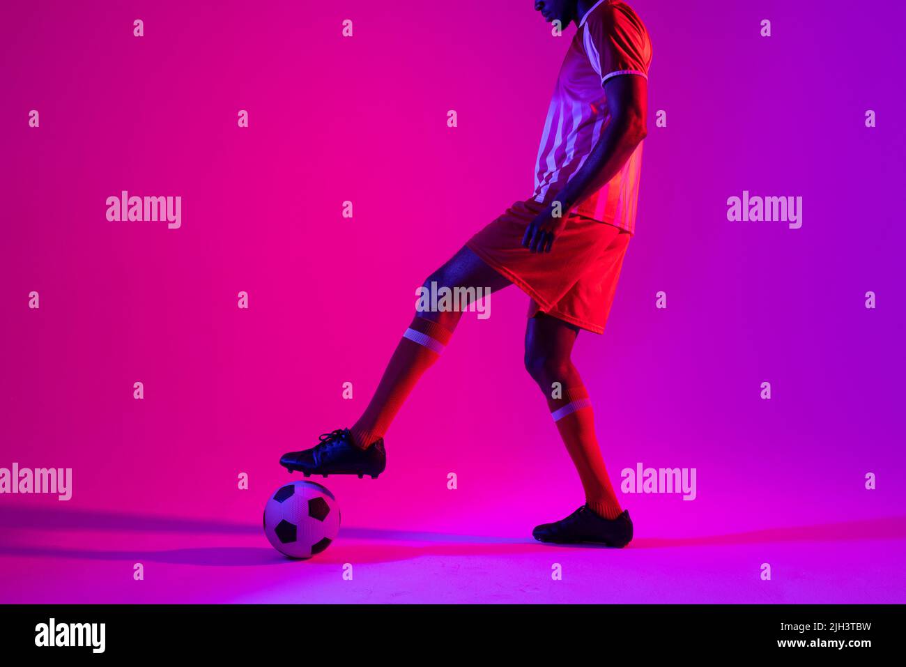 African american male soccer player with football over neon pink ...