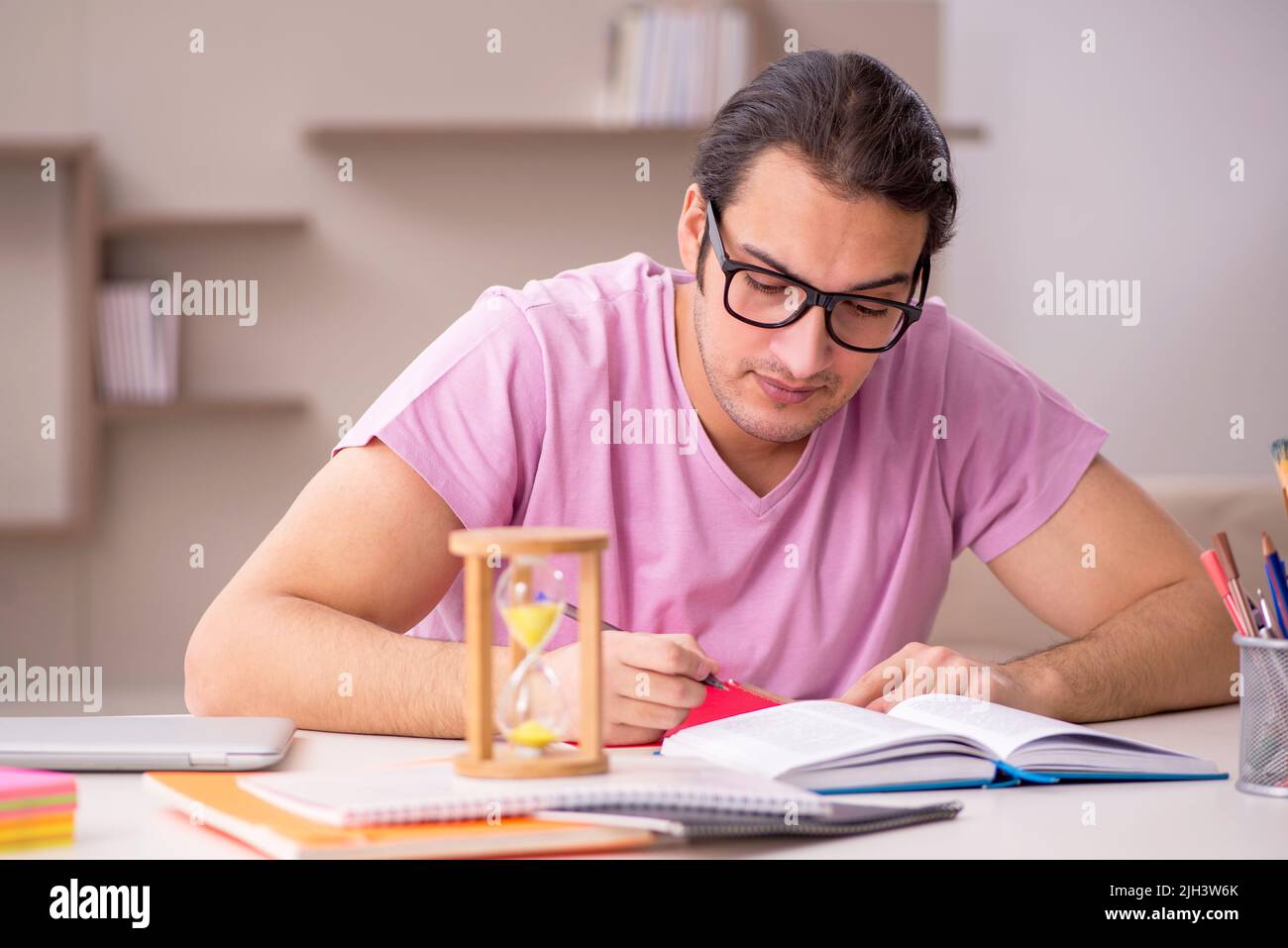 Young male student in time management concept at home Stock Photo - Alamy