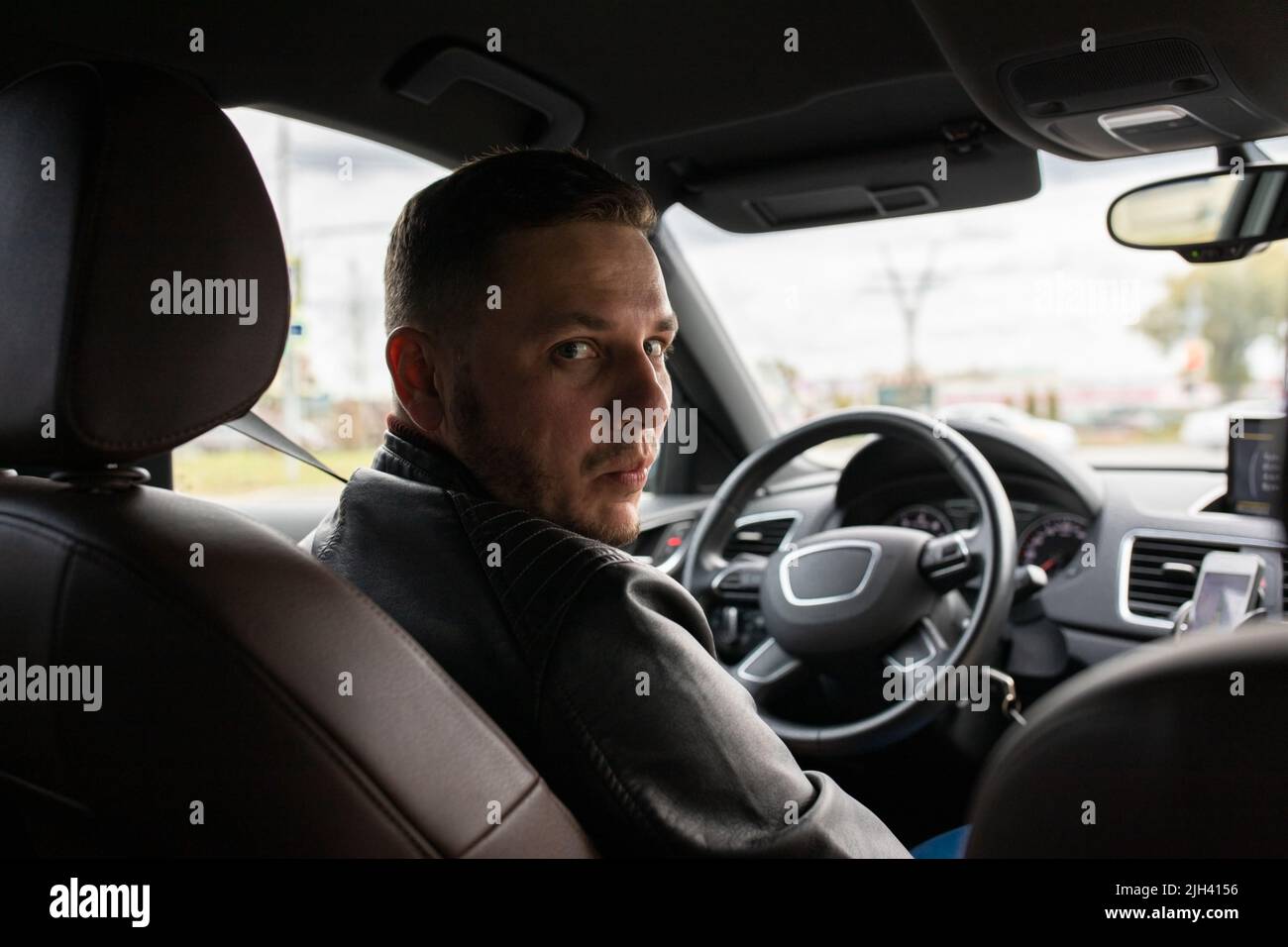 A man looks from behind the wheel of the car to the back of the car in ...
