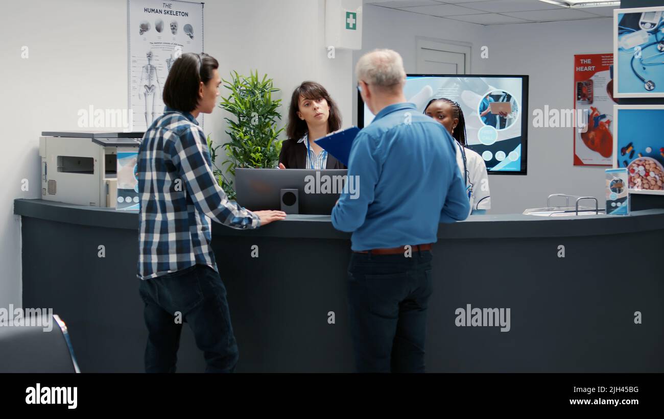 Busy hospital reception desk with many patients waiting to start examination appointment at ...