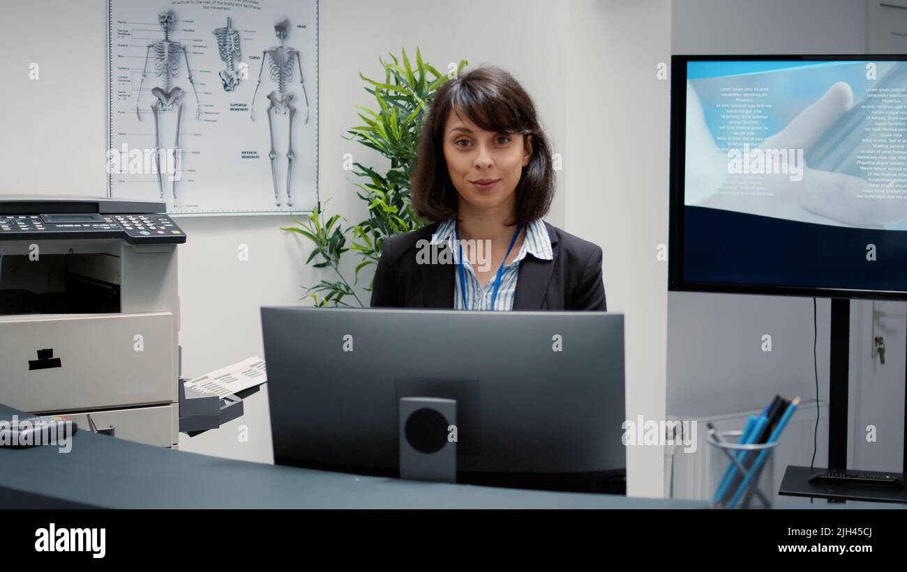Portrait of hospital reception desk employee working on medical service ...