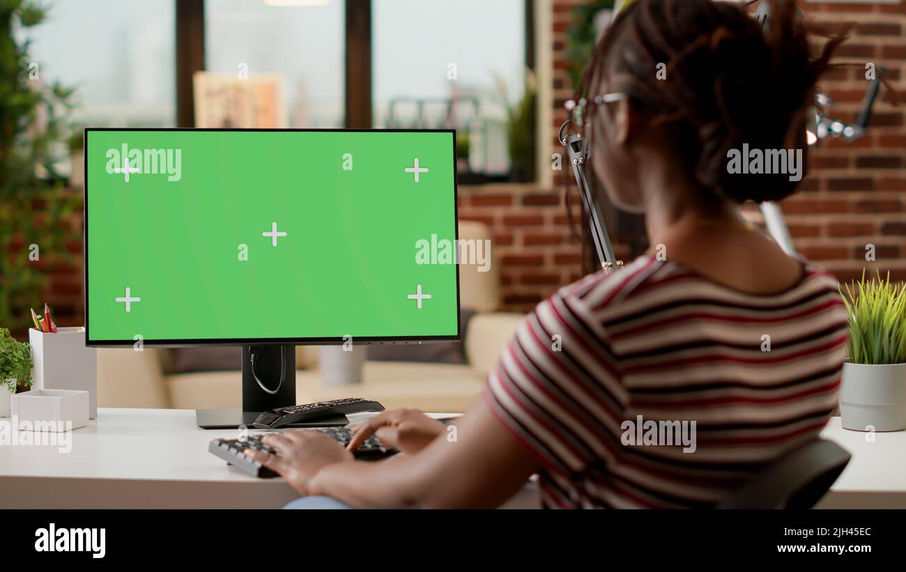 Female freelancer looking at computer with greenscreen, working ...