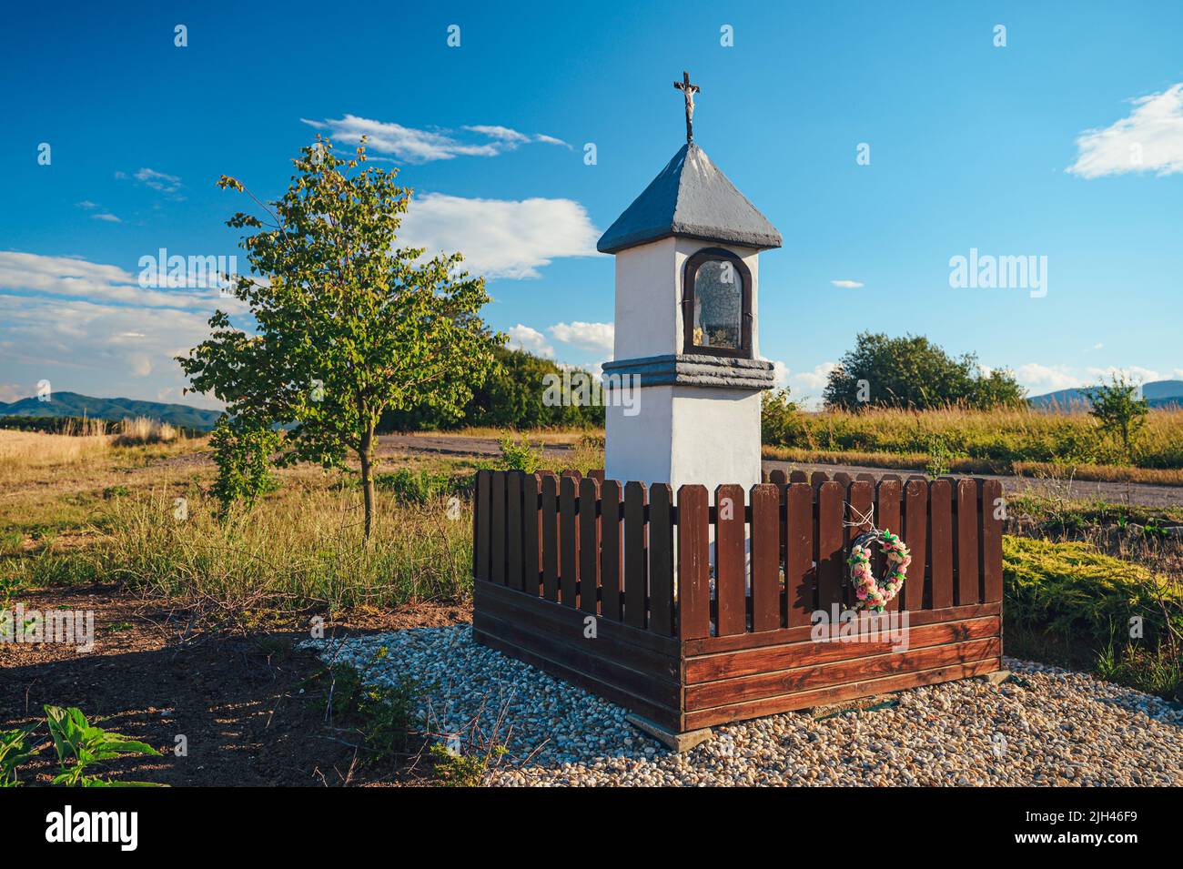 A Christian chapel in a village in a rural setting in a field. Cross on ...
