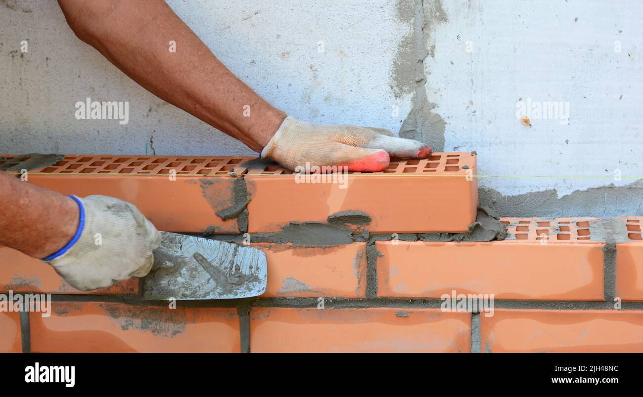 Close up on bricklaer hands laying house brick wall with trowel Stock ...