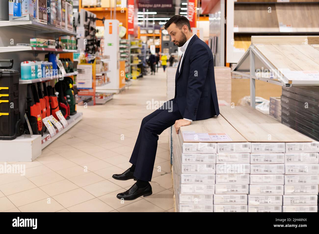 a buyer of a finishing goods store in a business suit sits on a stack ...