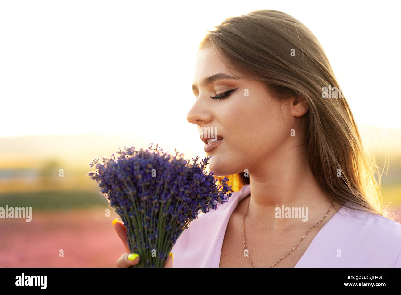 Close up portrait of a young woman holding bouquet of lavender whiile ...