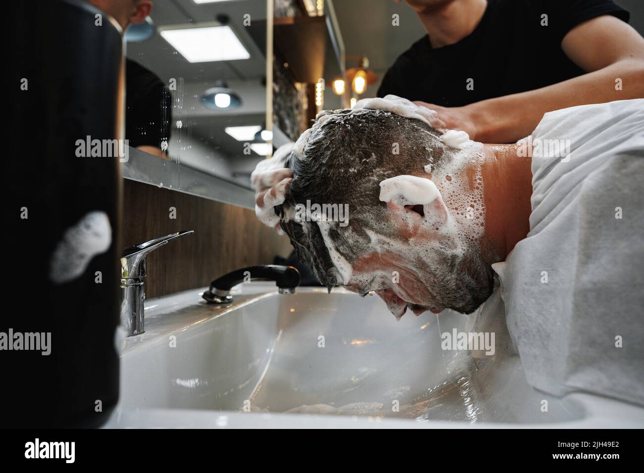 Hairdresser man washes client head in barbershop, close up Stock Photo ...
