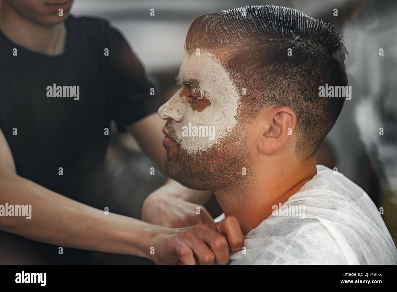 Relaxed man having purifying mask on face in a barbershop Stock Photo ...