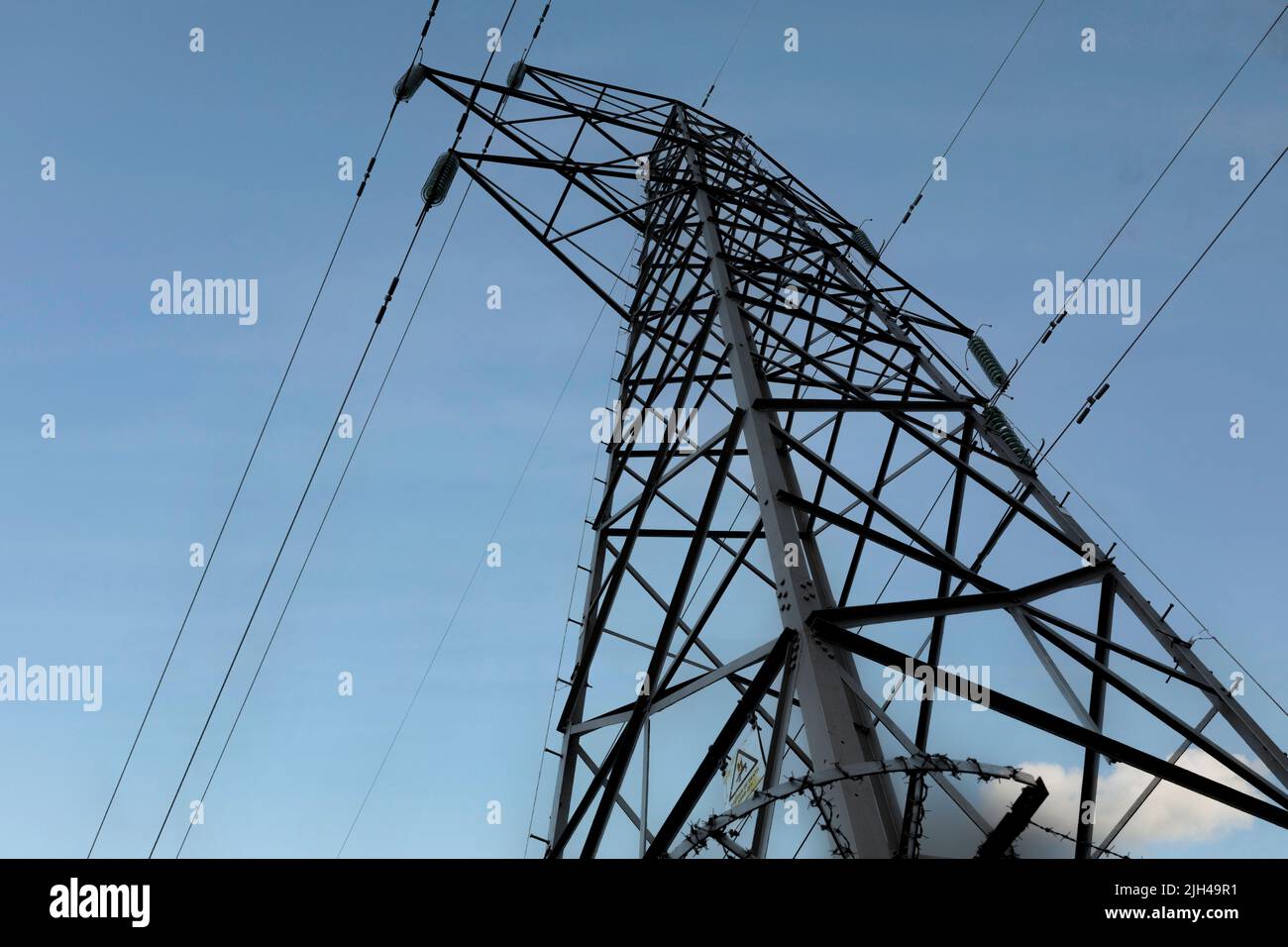 View from below of electricity pylon against deep blue sky with copy ...