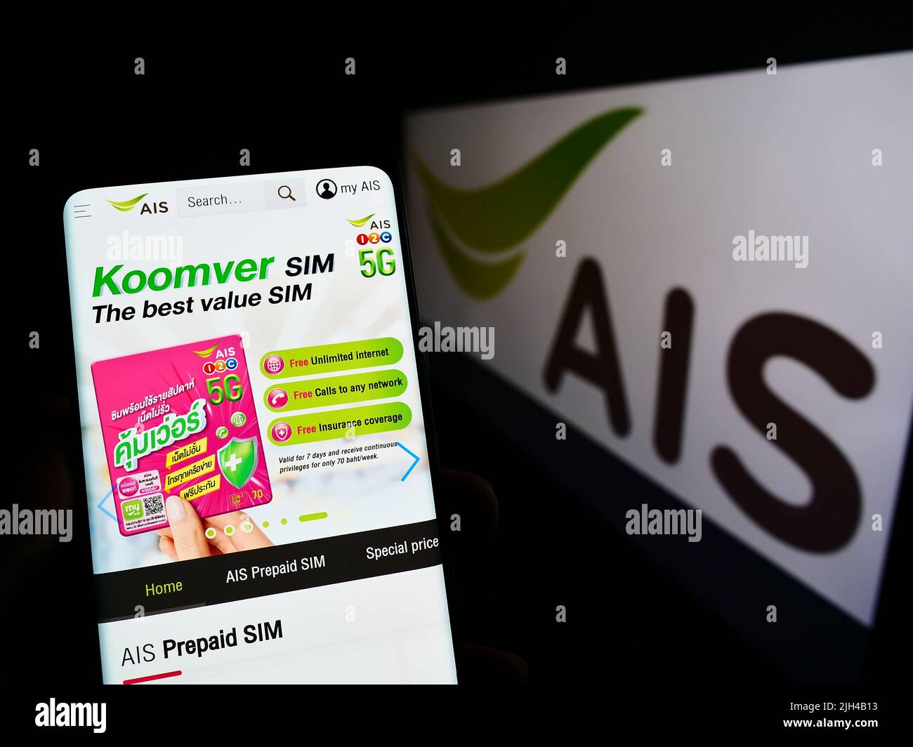 Person holding cellphone with webpage of Thai company Advanced Info Service (AIS) on screen in ...