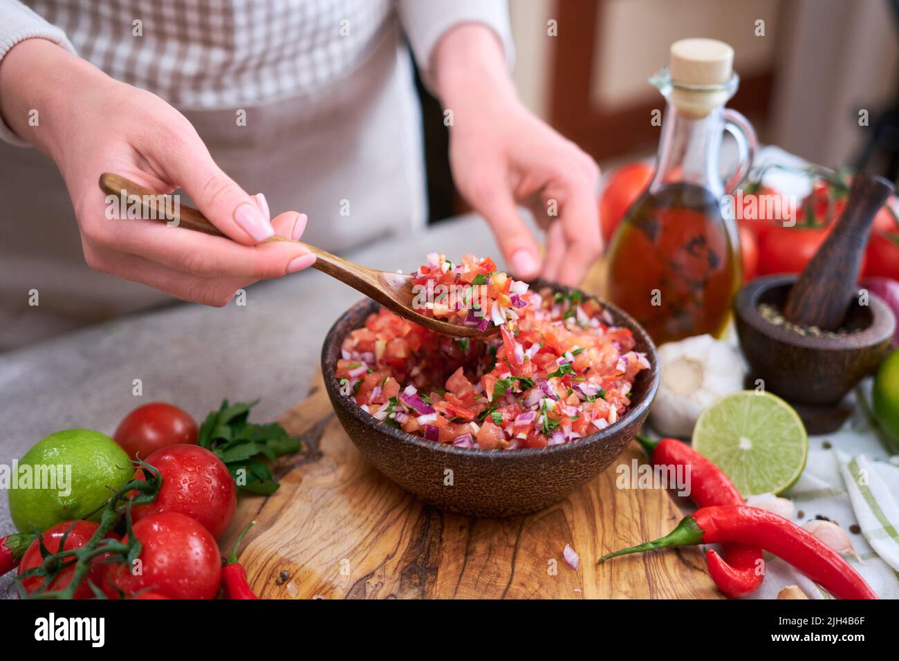 making salsa dip sauce - woman mixing chopped ingredients in wooden ...