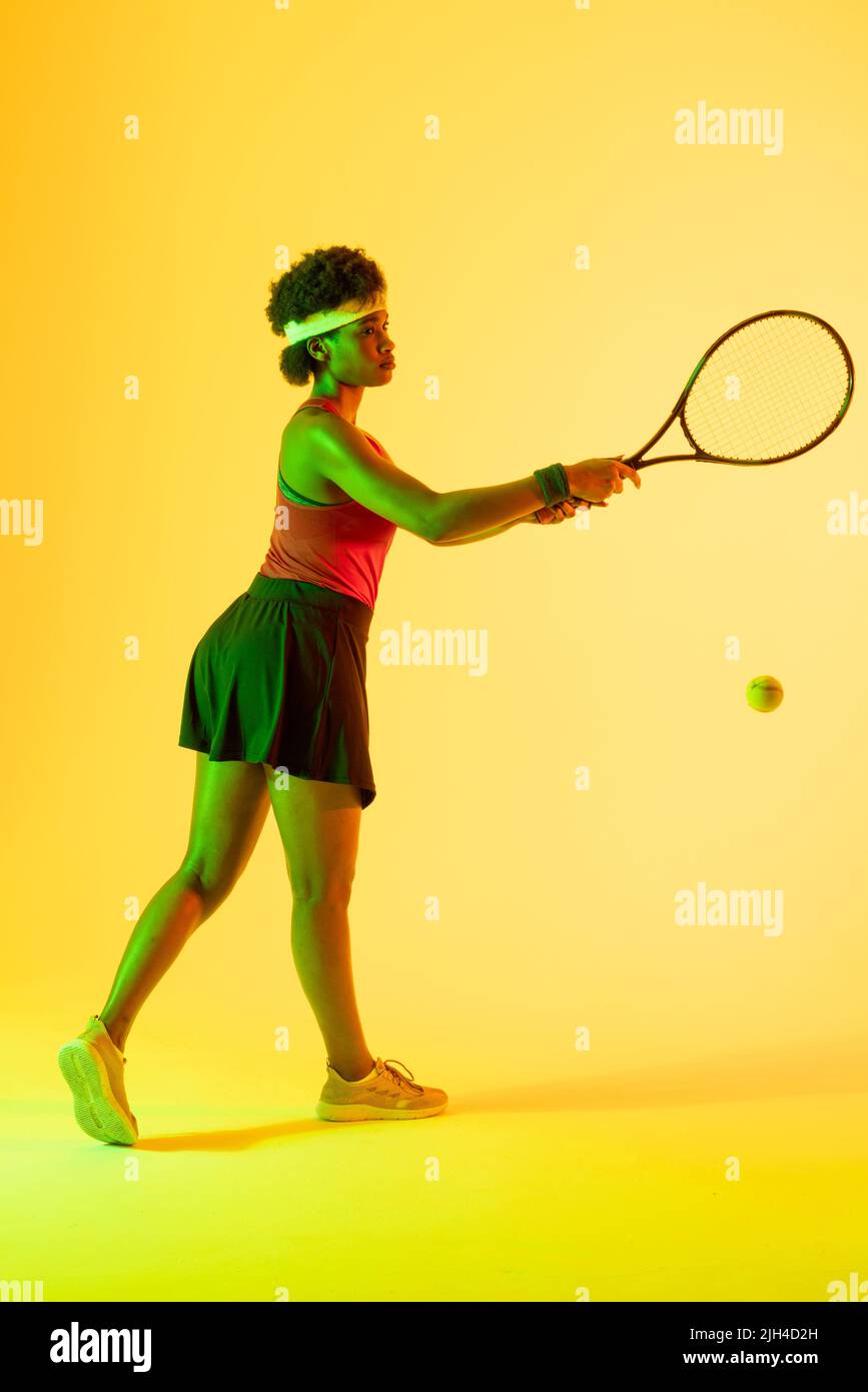 Vertical image of african american female tennis player hitting ball in ...