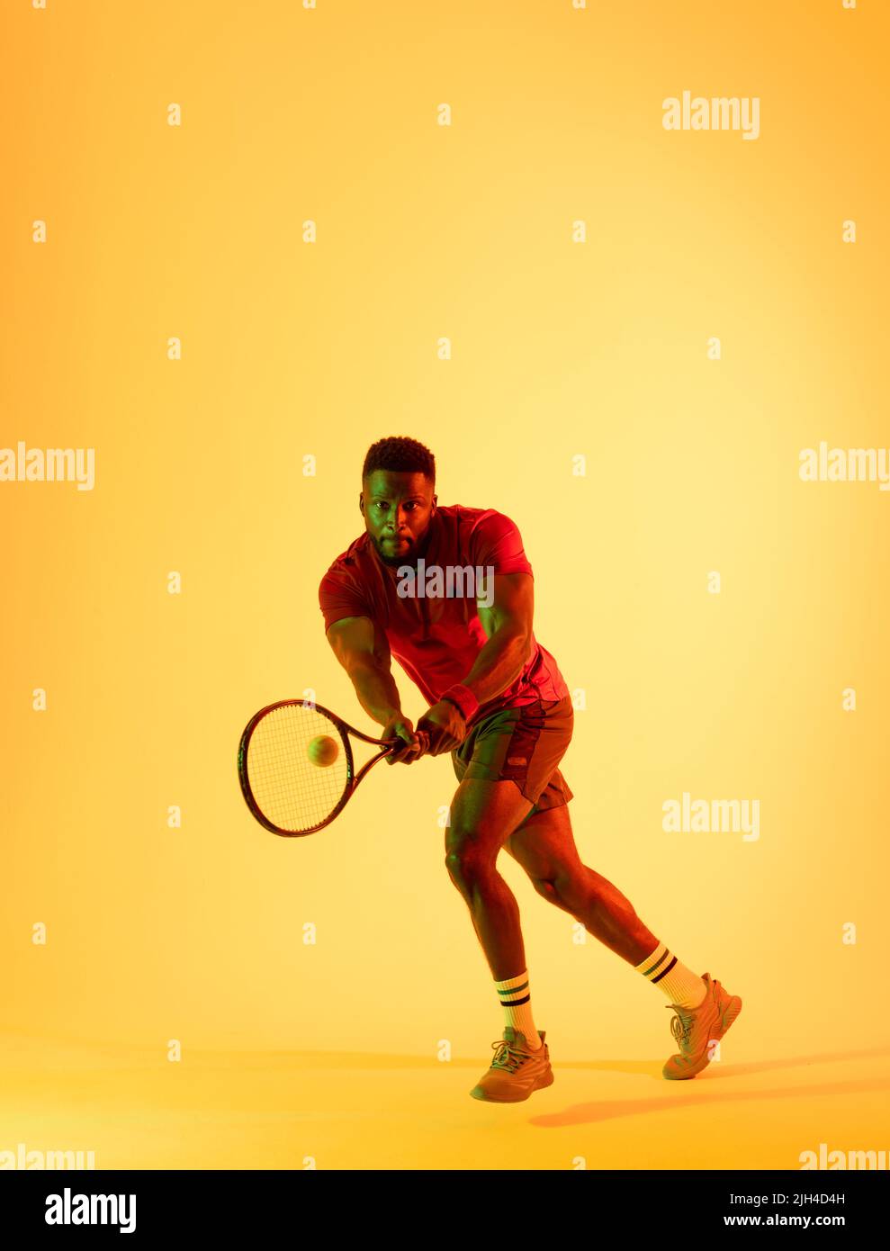 Vertical image of african american male tennis player hitting ball in ...