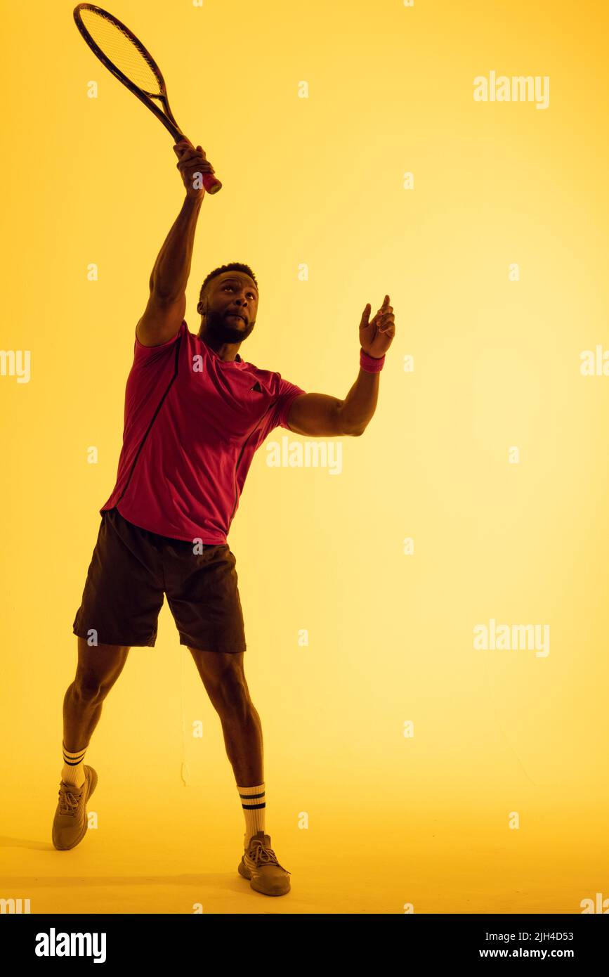 Vertical image of african american male tennis player hitting ball in ...