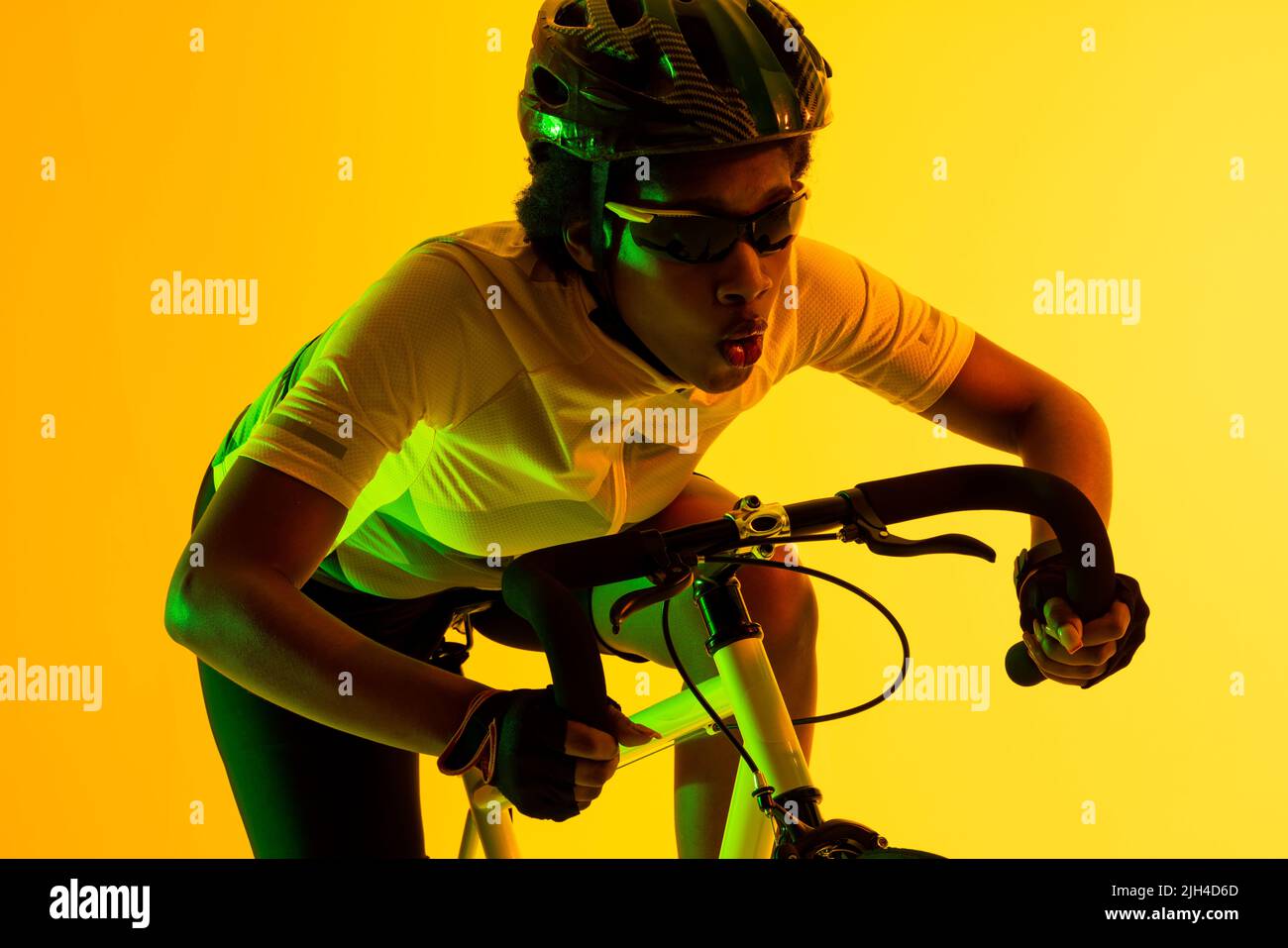 Image of african american female cyclist riding bike in yellow lighting ...