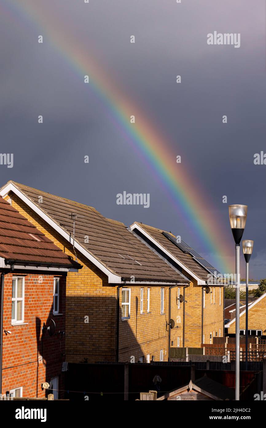 A prominent rainbow sits over the rooftops of a housing complex as a ...