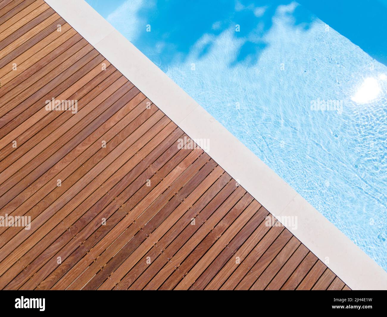Drone flight over pool with nice wooden terrace surrounded by green ...