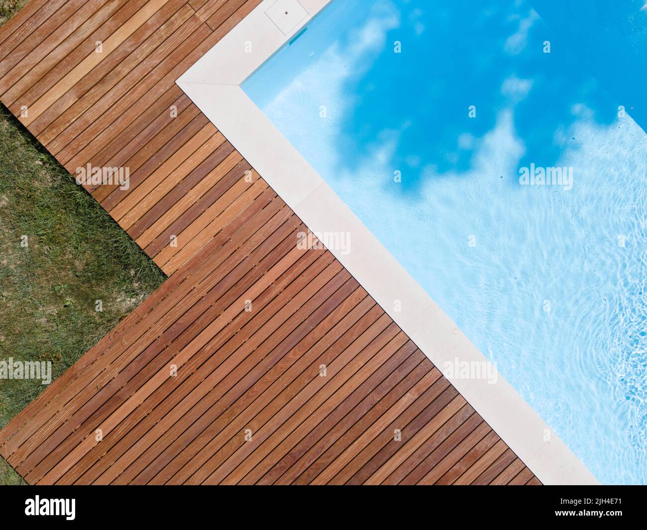 Drone flight over pool with nice wooden terrace surrounded by green ...