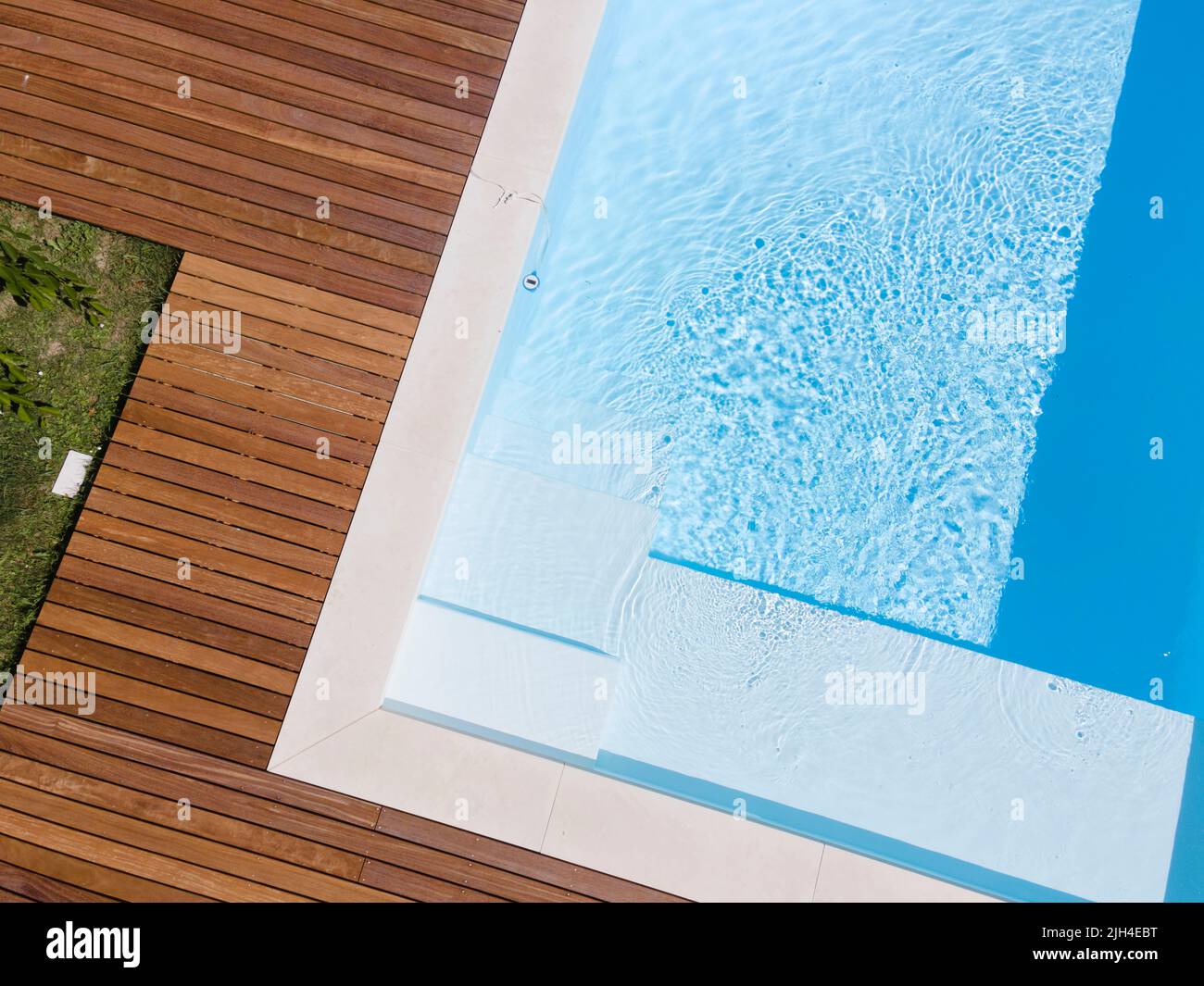 Drone flight over pool with nice wooden terrace surrounded by green ...