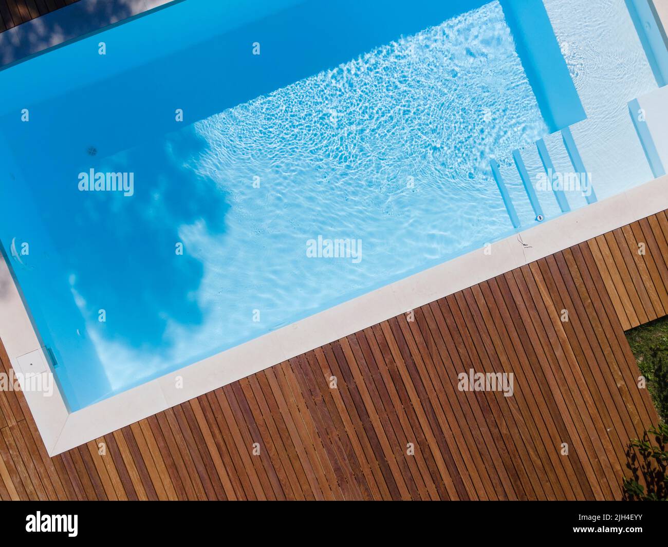 Drone flight over pool with nice wooden terrace surrounded by green ...