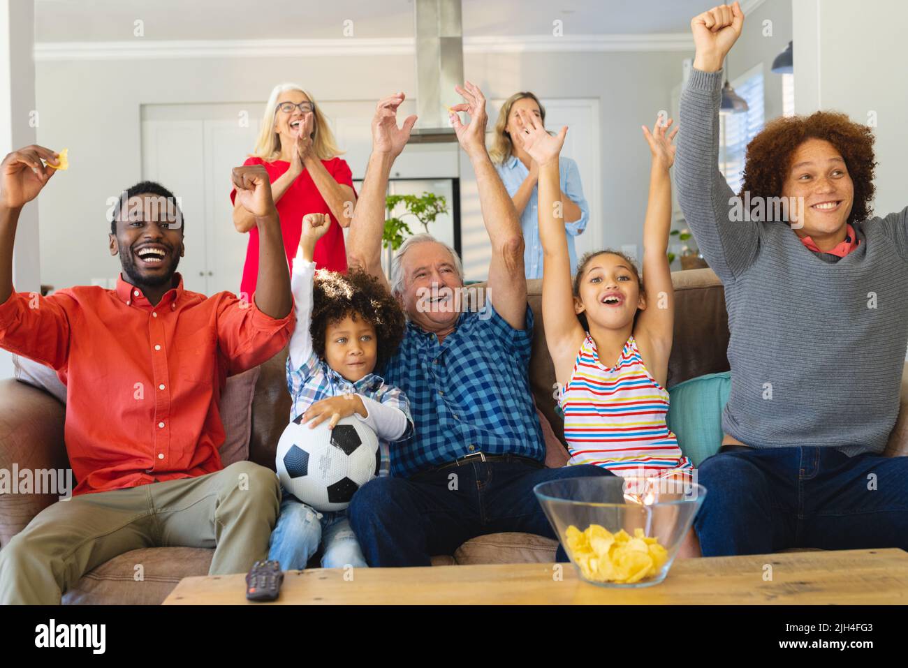 Multiracial multigeneration family with arms raised celebrating victory ...