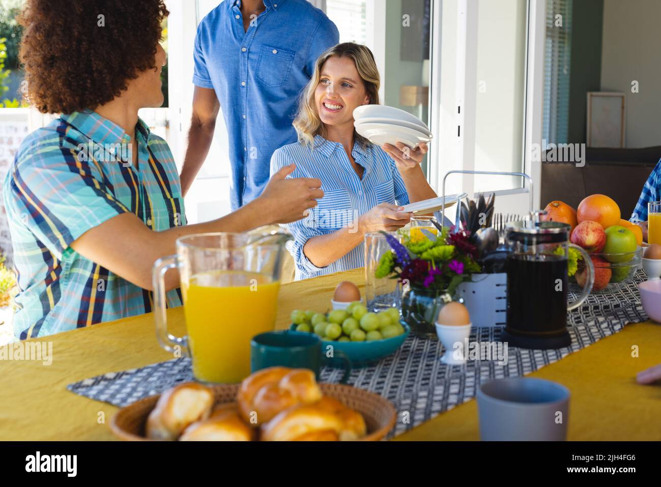 Caucasian young woman passing plates to biracial young man while having ...