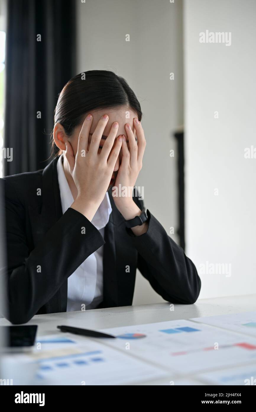 Sad and unhappy young Asian businesswoman sits at her office desk ...