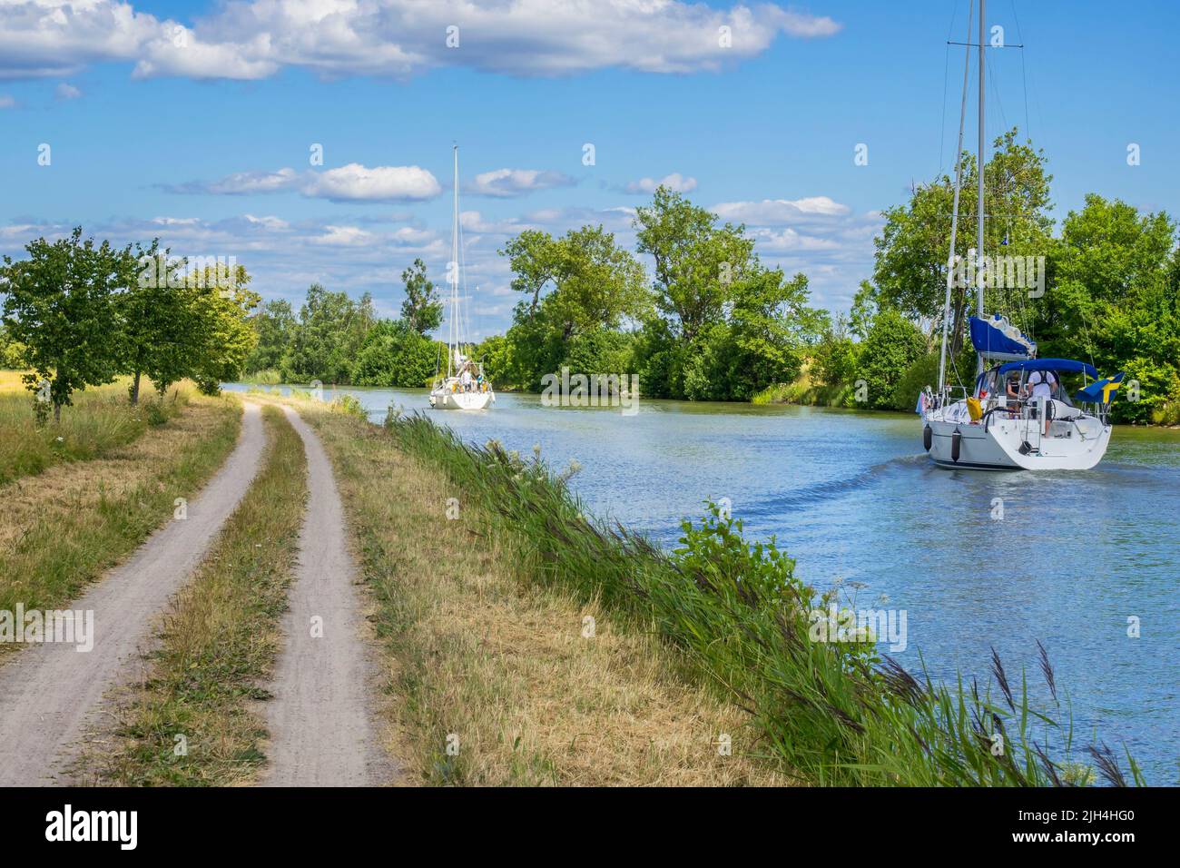 Canal with boats and a gravel road Stock Photo - Alamy