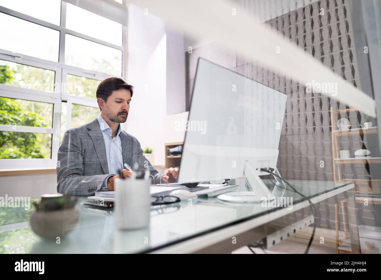Businessperson Calculating Invoice With Computer On Desk Stock Photo ...