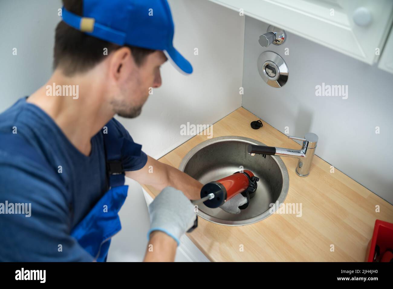 Plumber Cleaning Drain And Sink Using Pump Stock Photo - Alamy