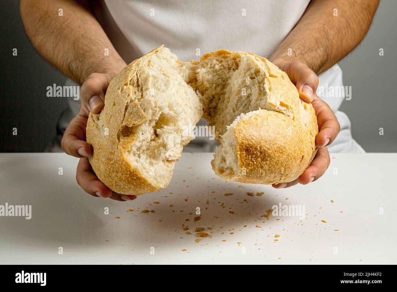 Mens hands break a loaf of round wheat bread made with sourdough Stock ...