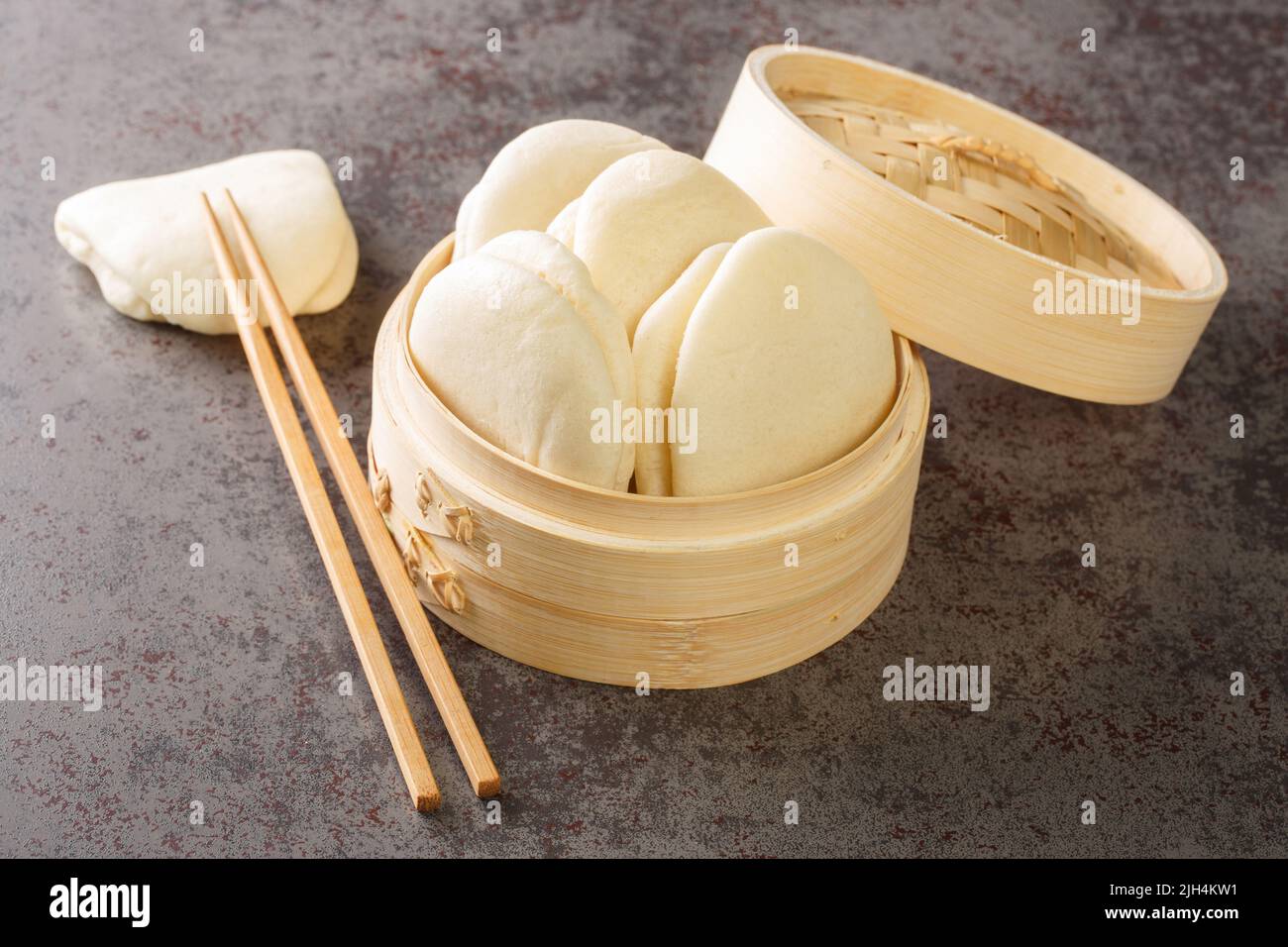 Chinese food Gua bao buns in bamboo steamer closeup on the table ...